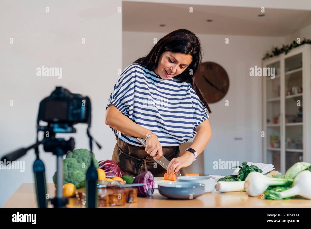 Woman cutting carrot filming through camera at home Stock Photo - Alamy