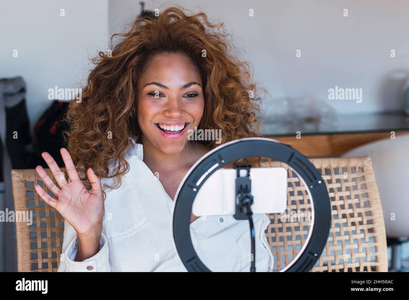 Young Influencer waving hand to mobile phone at home Stock Photo - Alamy