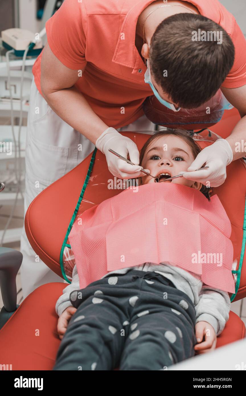 The dentist examines the baby girl's baby teeth, the treatment of baby ...