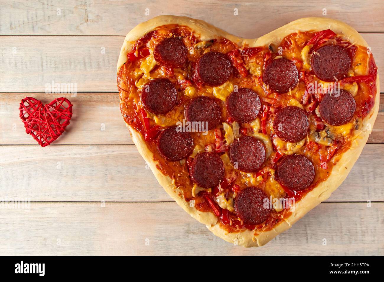 Heart shaped pepperoni pizza on a wooden background. Valentines day ...