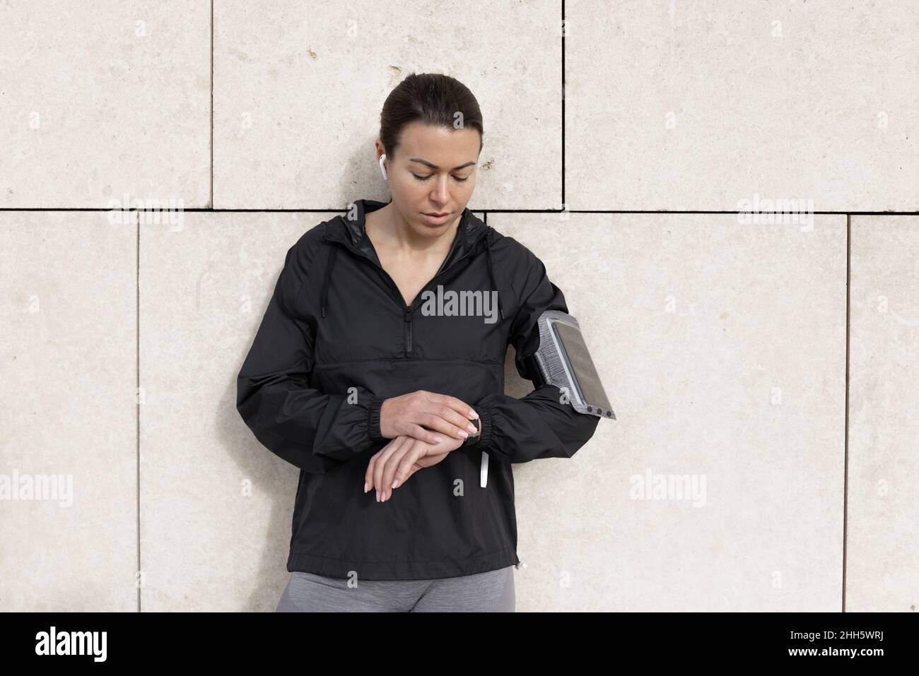 Woman checking time on smart watch standing in front of wall Stock ...