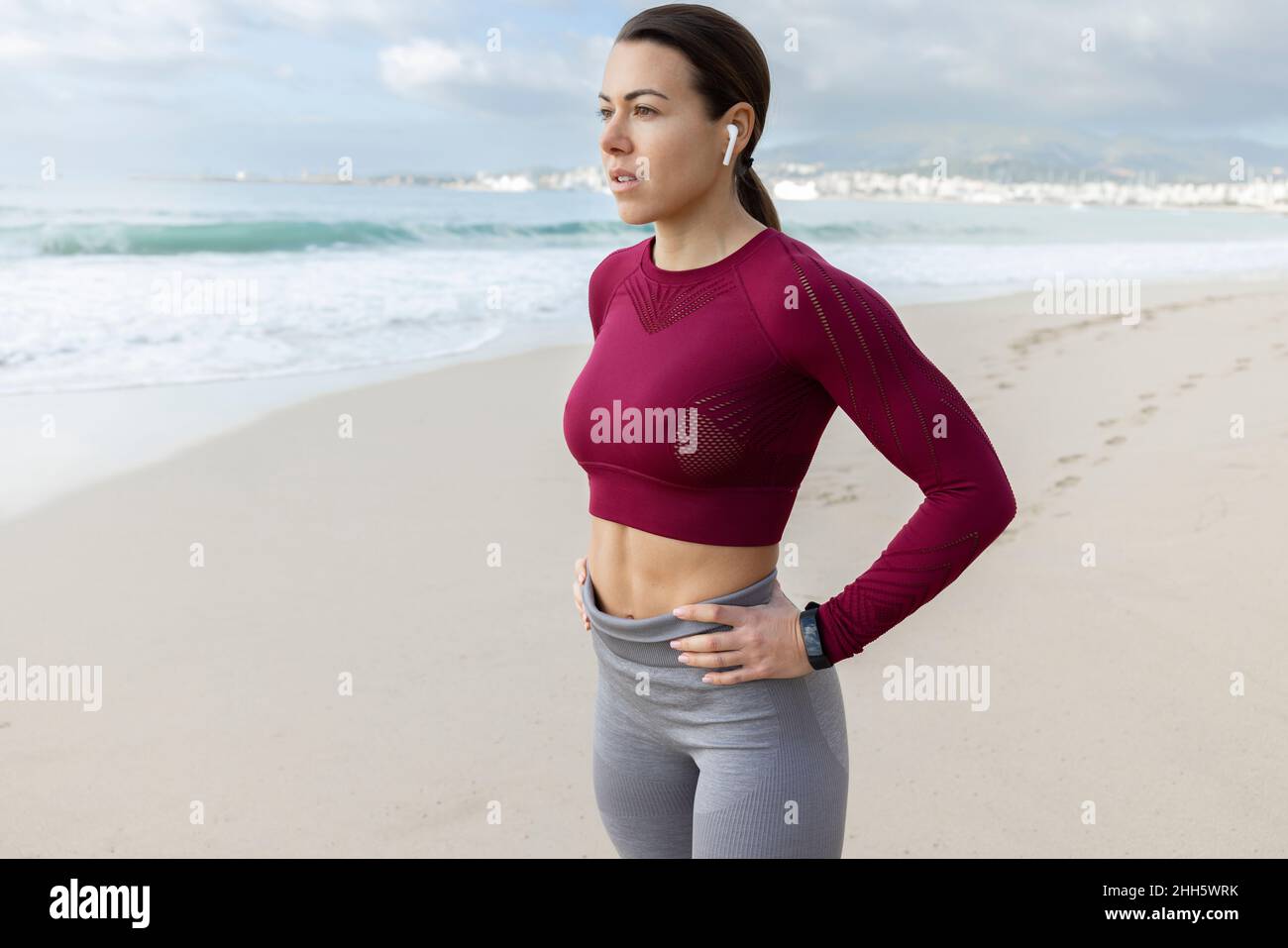 Fit woman standing with hands on hips at beach Stock Photo - Alamy