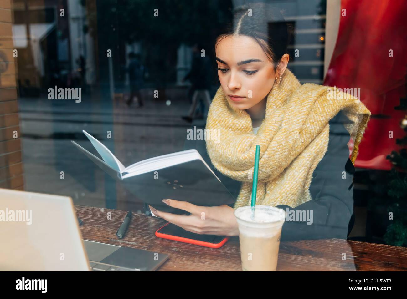 Focused girl reading diary at table in cafe Stock Photo - Alamy