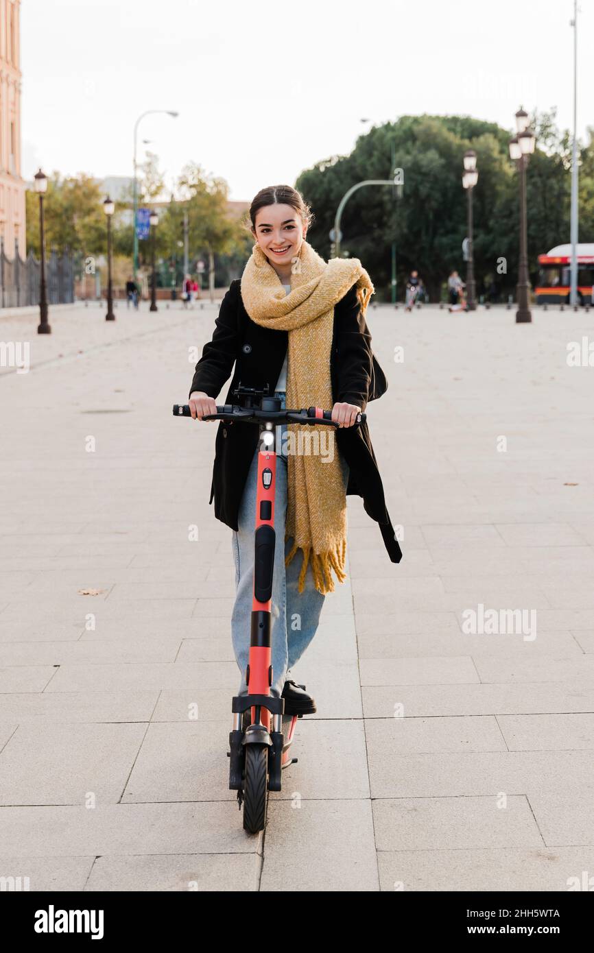 Happy teenager riding electric push scooter on footpath Stock Photo - Alamy