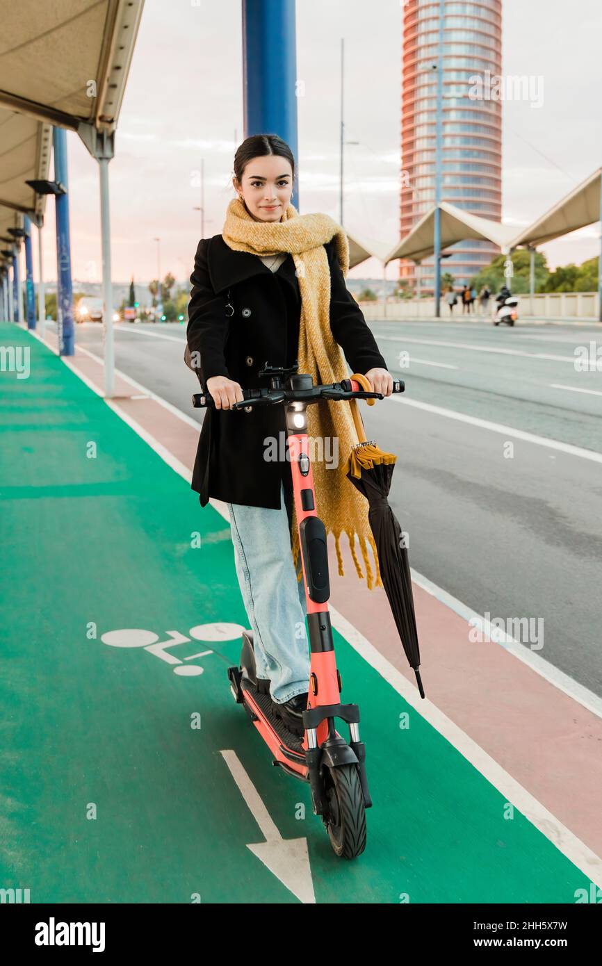 Smiling teenager riding electric push scooter on bicycle lane Stock ...