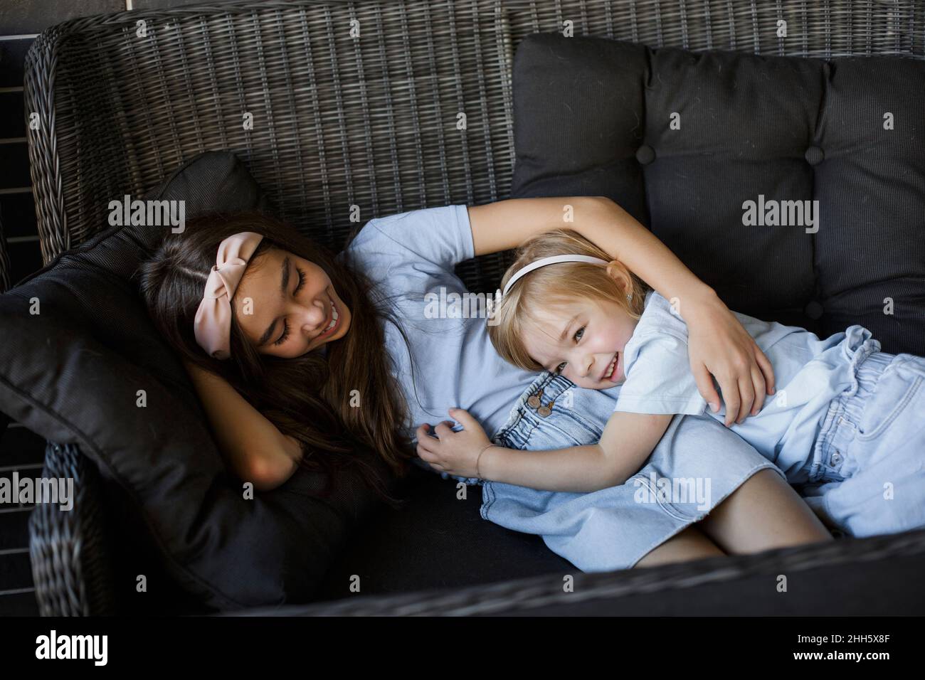Happy siblings lying on sofa at patio Stock Photo - Alamy