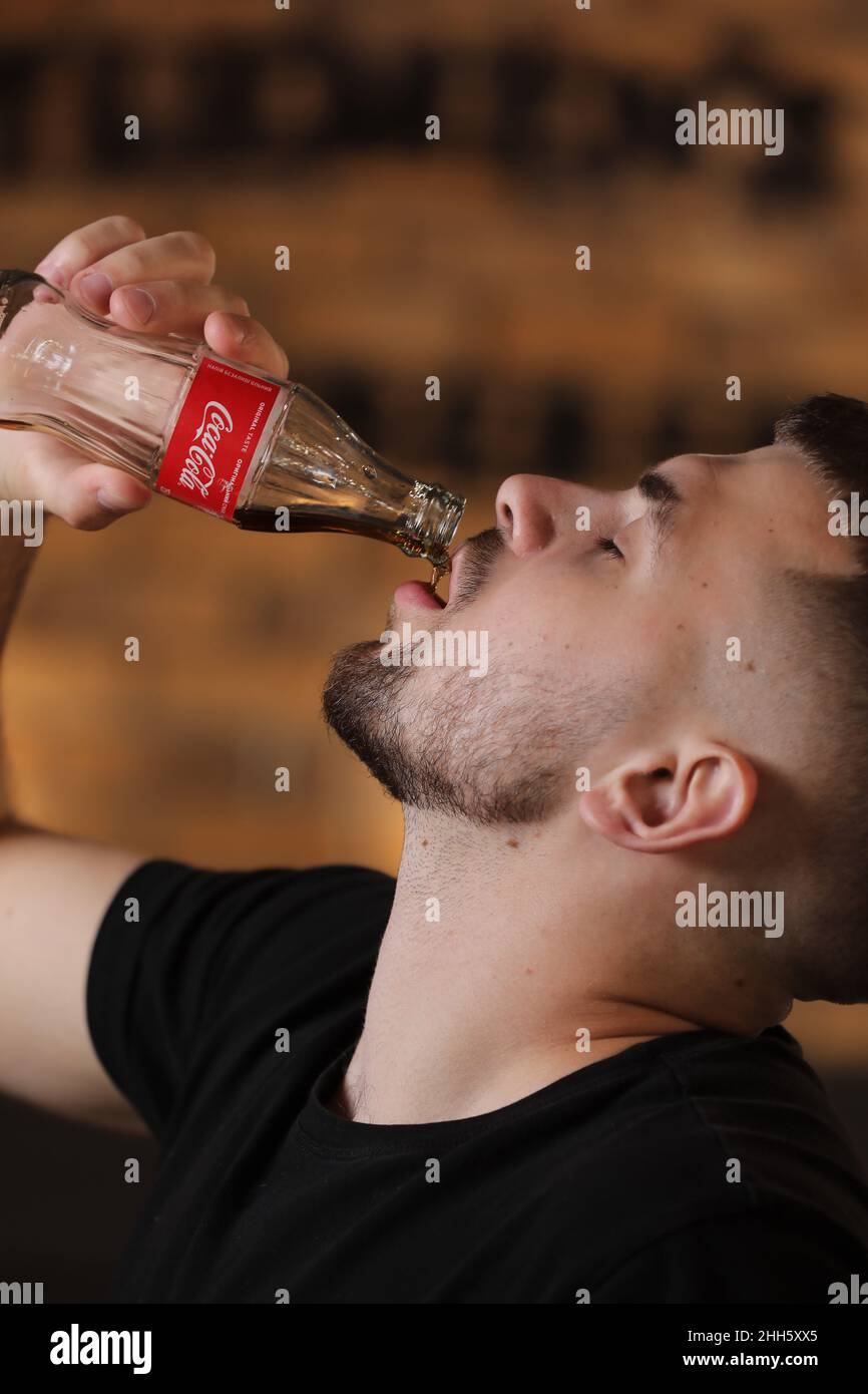 RIVNE, UKRAINE JUNE 26 2020: young bearded man drinking coca cola from ...