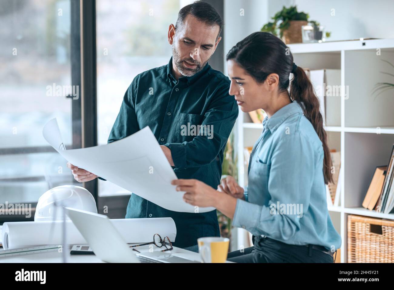 Architects discussing floor plan in small office Stock Photo - Alamy