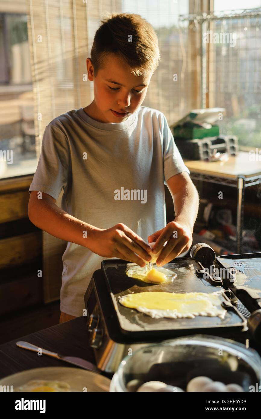 Boy preparing fried egg in kitchen at home Stock Photo - Alamy