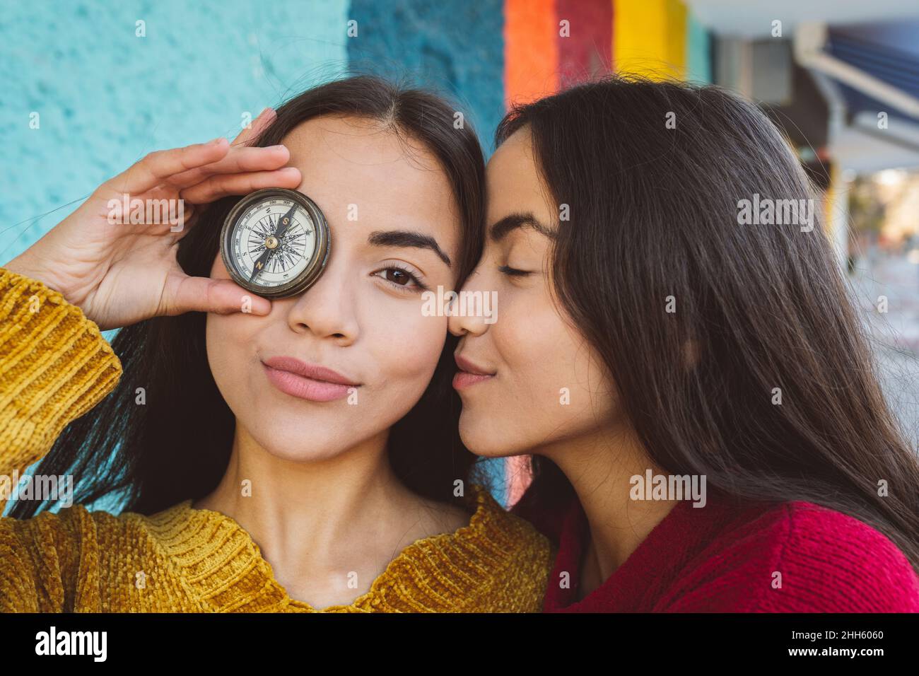 Young woman covering eye with compass by twin sister Stock Photo - Alamy