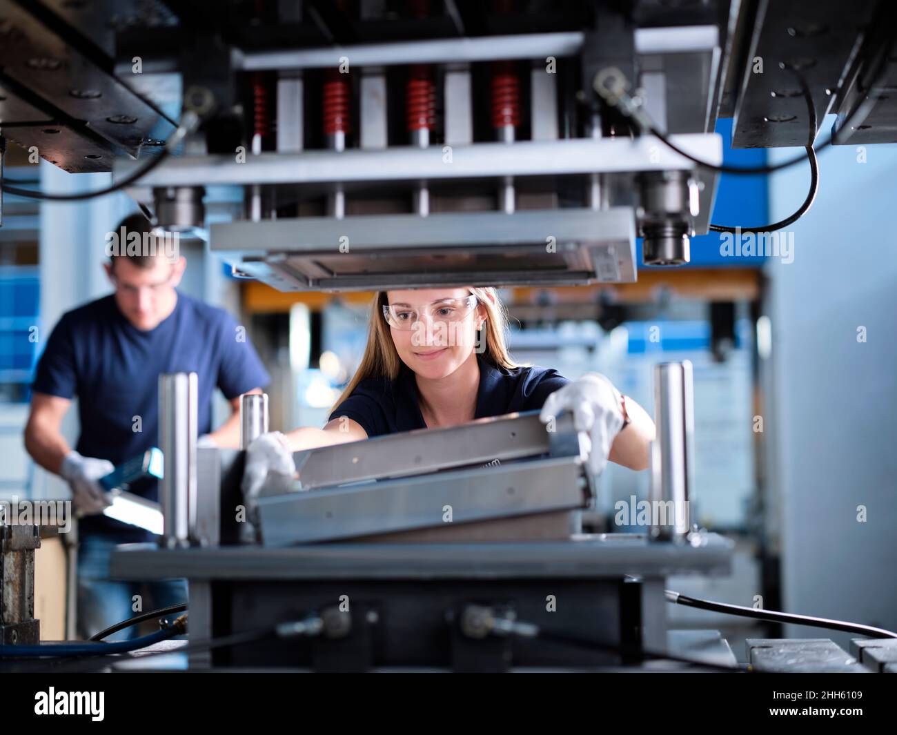Engineer adjusting metal frames in machine at factory Stock Photo - Alamy