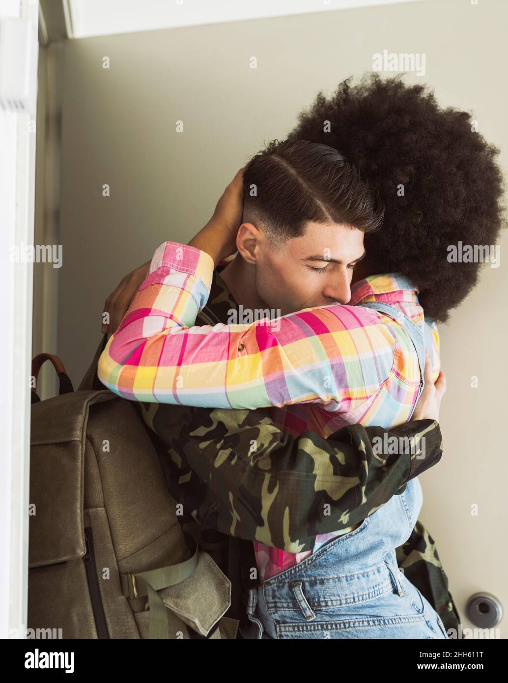 Young woman welcoming and embracing soldier man at doorway Stock Photo ...