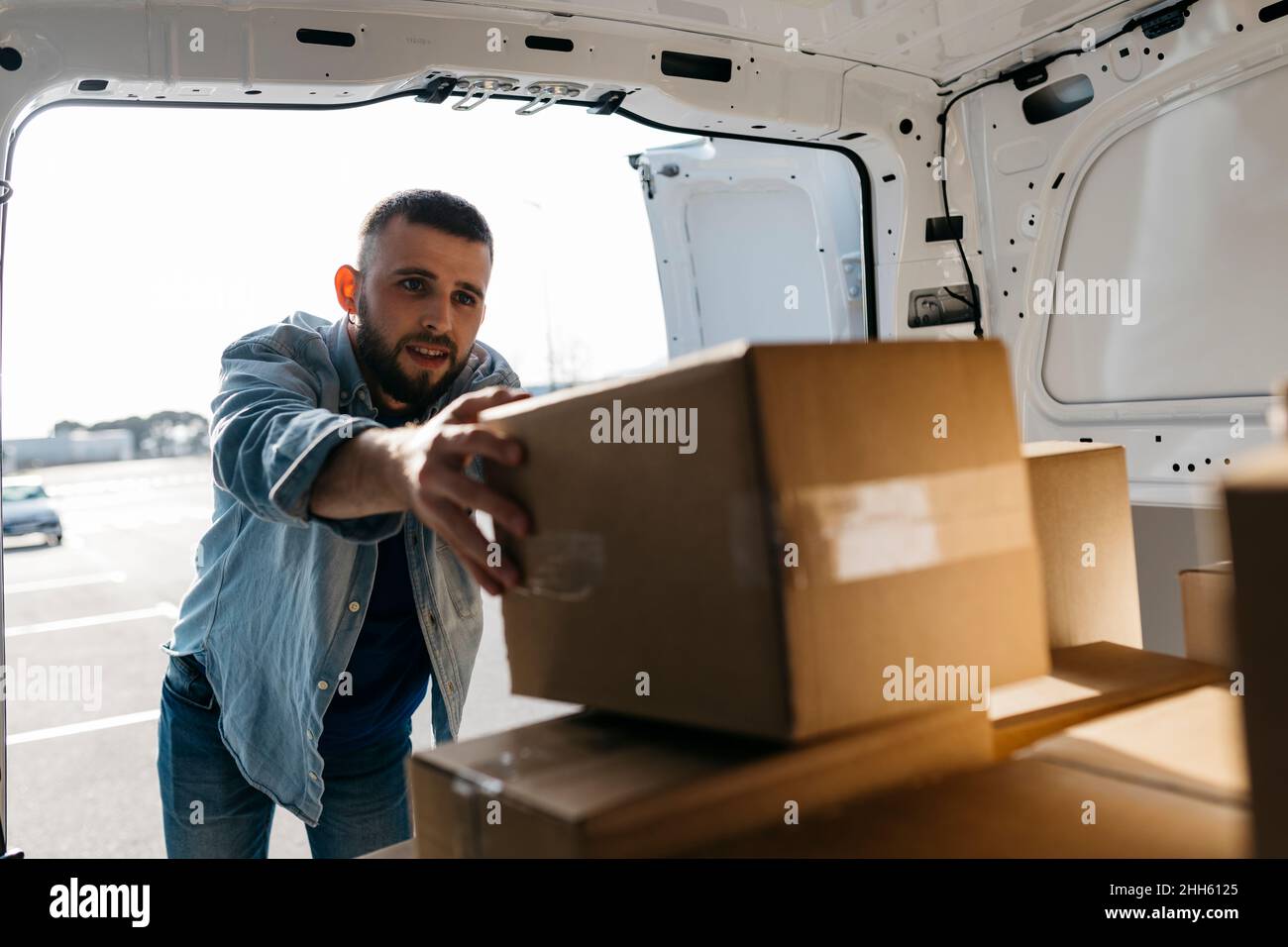 Delivery man arranging boxes in van Stock Photo - Alamy