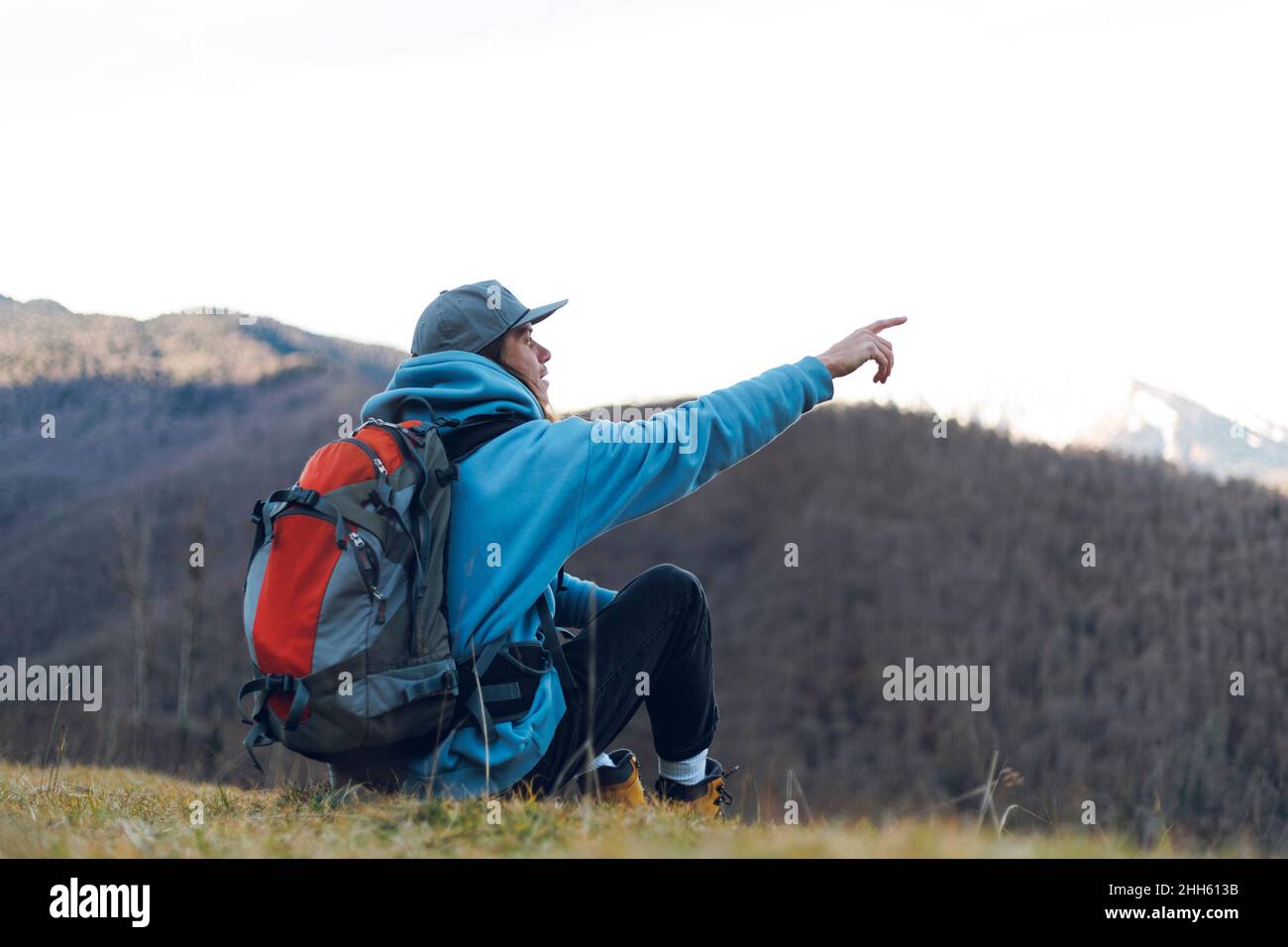 Hiker with backpack pointing at clear sky Stock Photo - Alamy