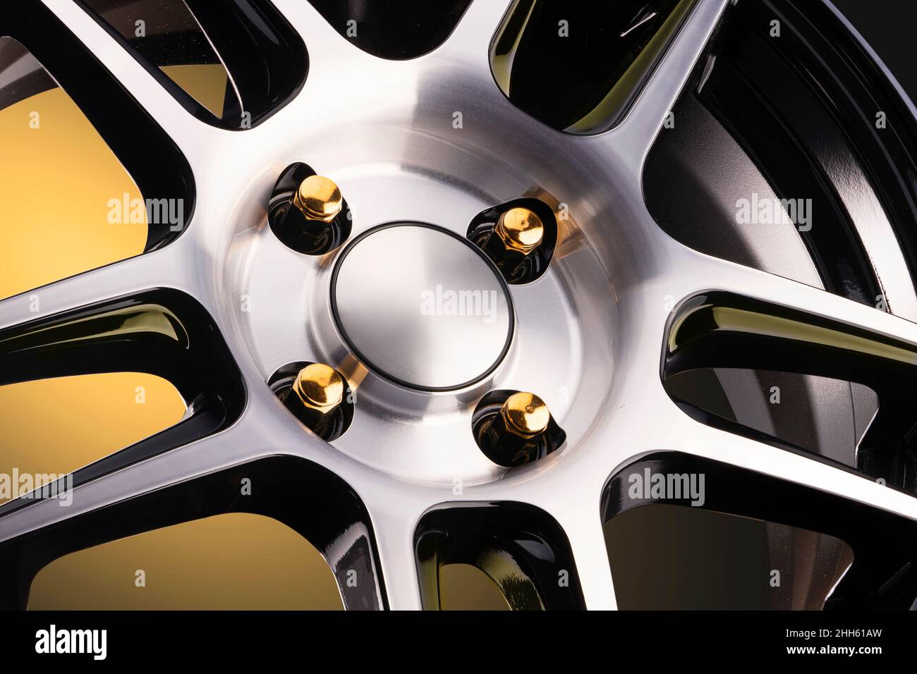 bright yellow alloy wheel and wheel nuts on a gradient black and yellow ...
