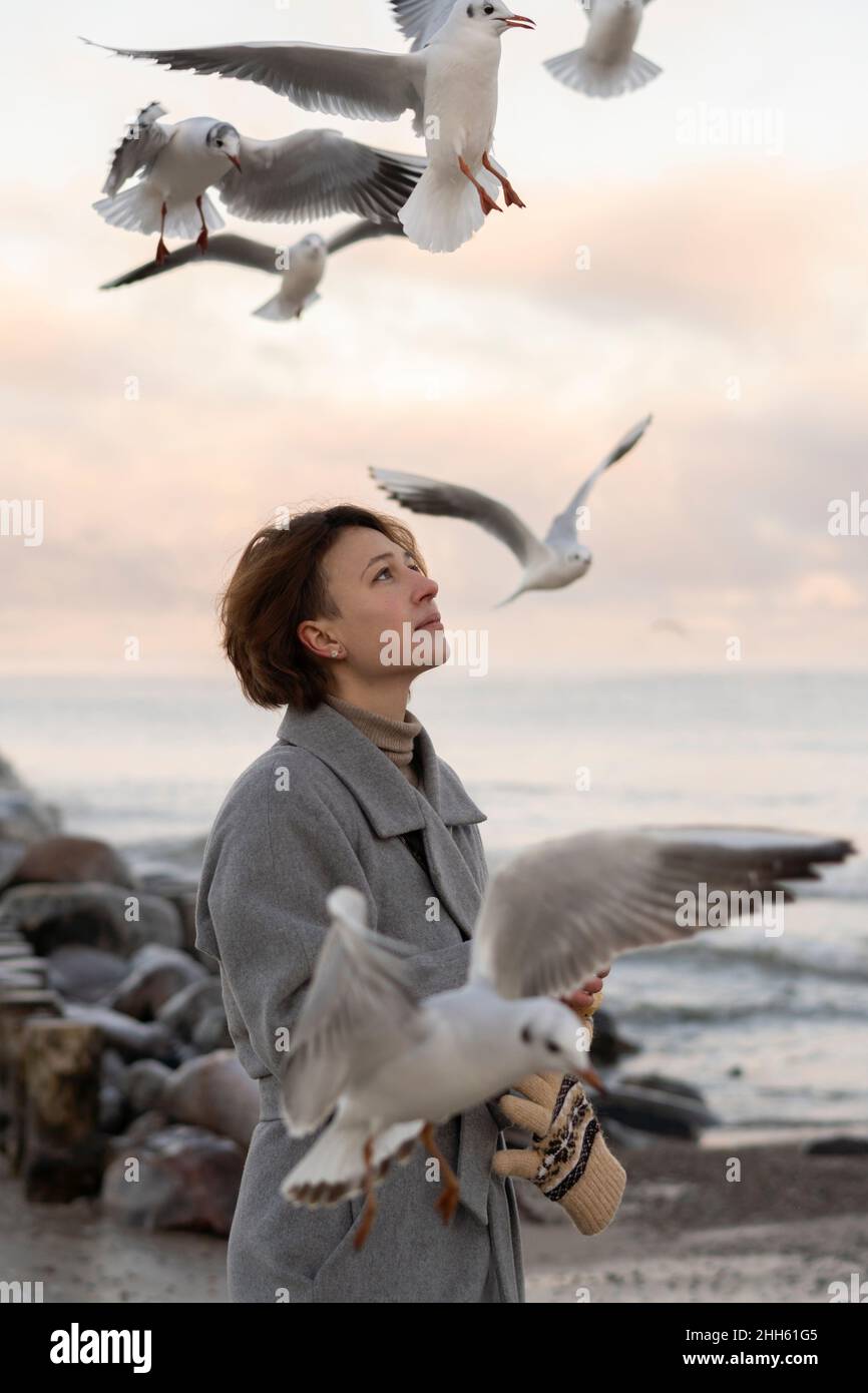 Thoughtful woman amidst flying seagulls at beach Stock Photo - Alamy
