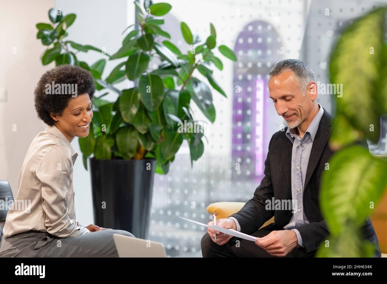 Smiling colleagues looking at document in office Stock Photo - Alamy