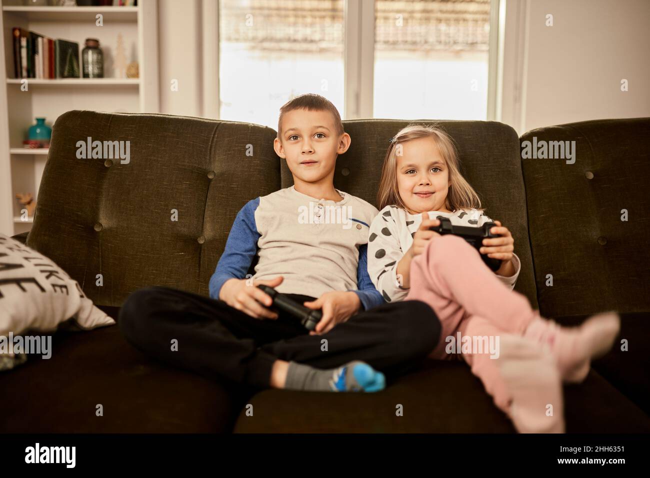 Sibling playing video game through joystick at home Stock Photo - Alamy