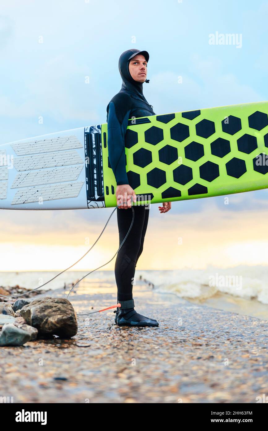 Confident surfer standing with surfboard on pier Stock Photo - Alamy
