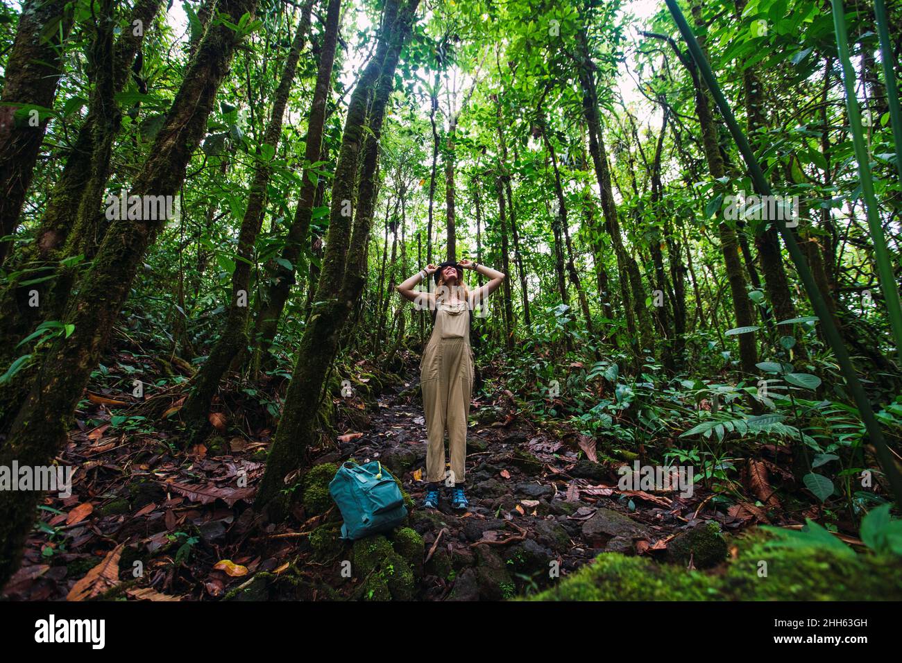 Young woman amidst trees hiking in forest at Arenal Volcano National ...