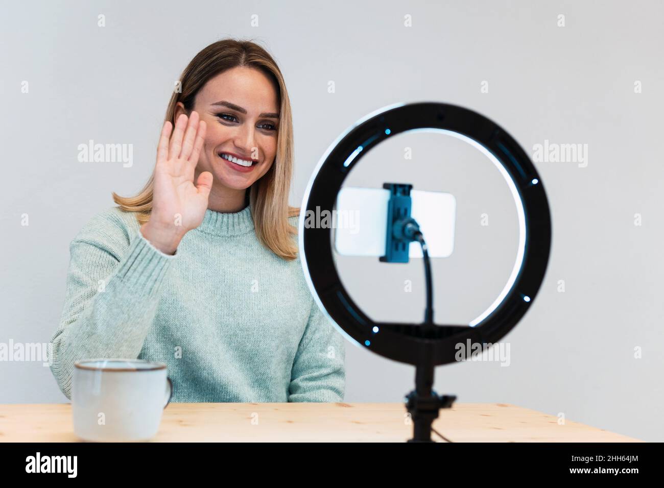 Smiling influencer waving during tutorial sitting in front of ring ...