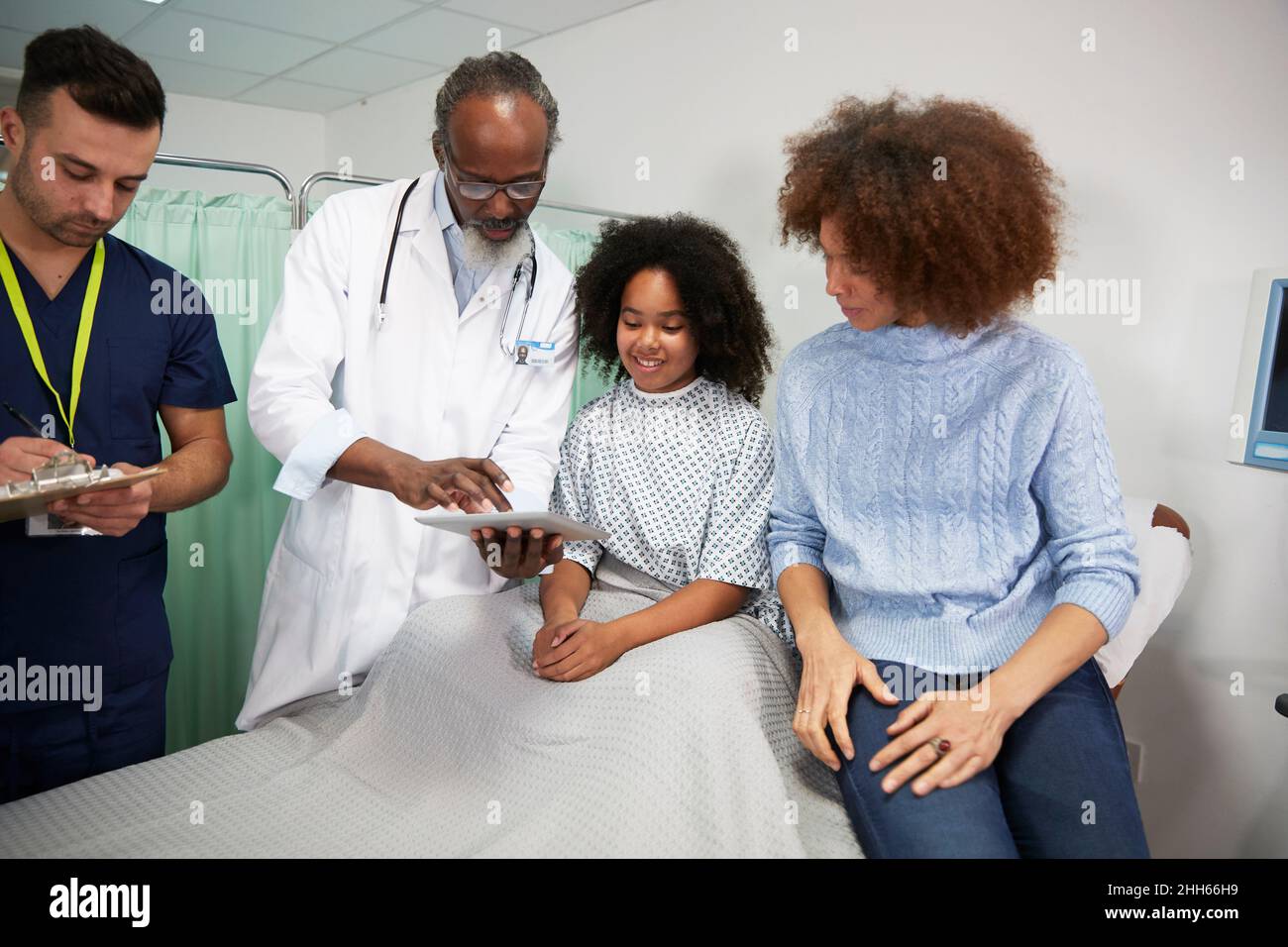 Patient with mother reviewing report over tablet PC held by doctor at ...