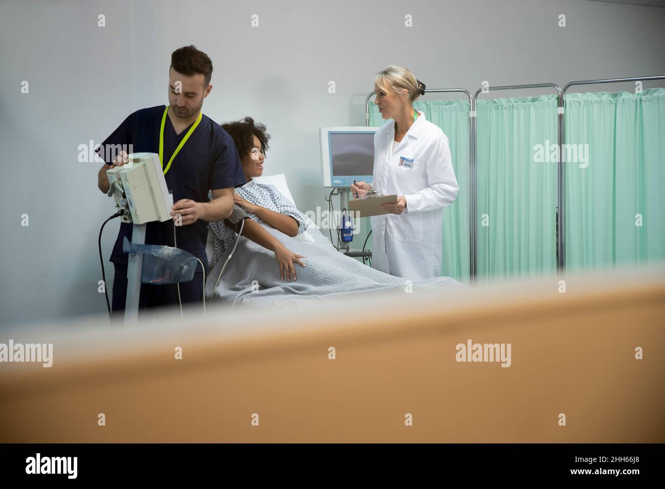 Nurse operating blood pressure machine with patient and doctor talking ...
