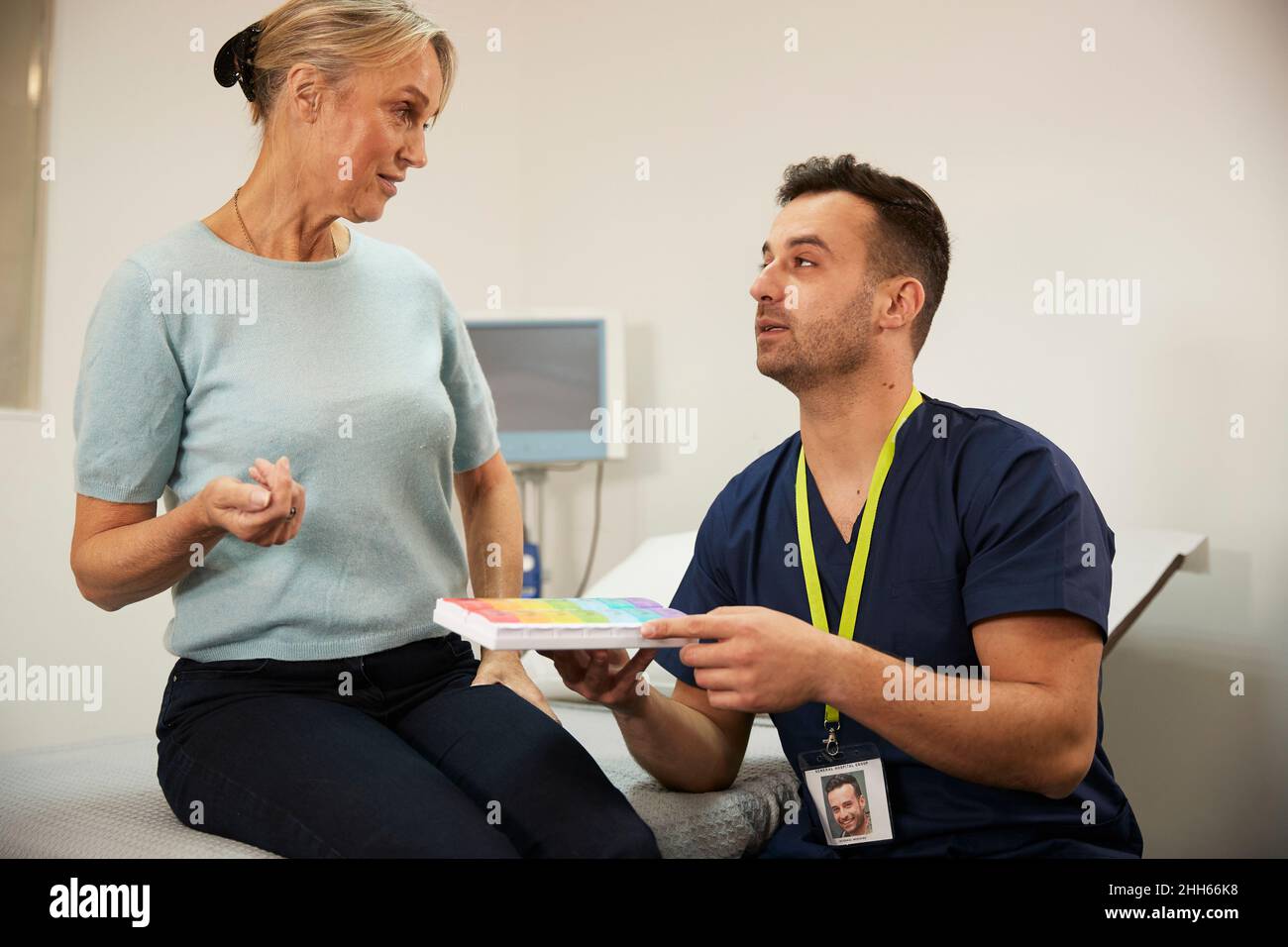 Nurse holding medicine box talking to patient in medical room Stock ...
