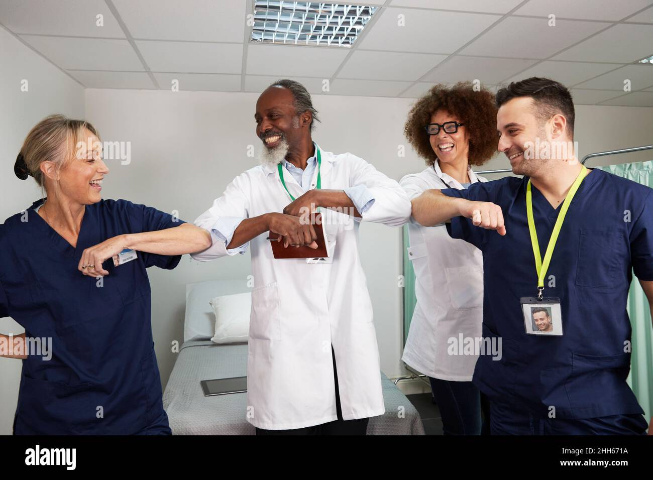 Happy healthcare workers giving elbow bumps in medical room Stock Photo ...