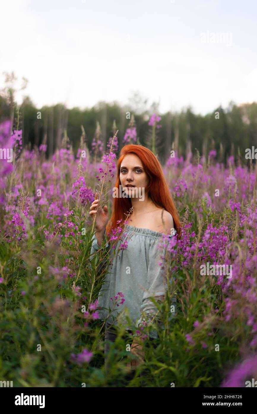 Redhead woman amidst pink flowers in field Stock Photo - Alamy