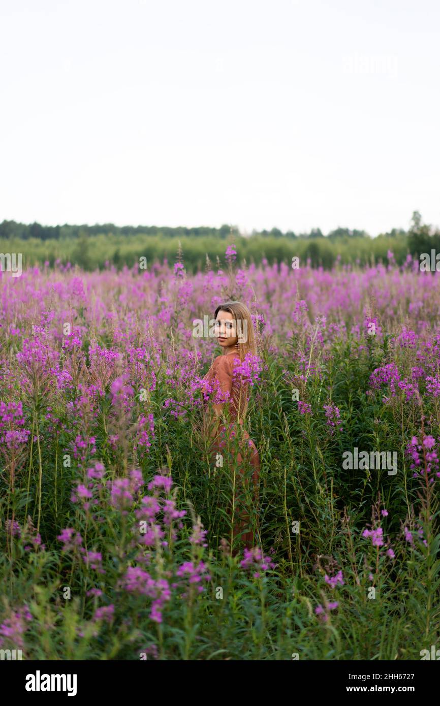 Young woman amidst pink flowering plants in meadow Stock Photo - Alamy