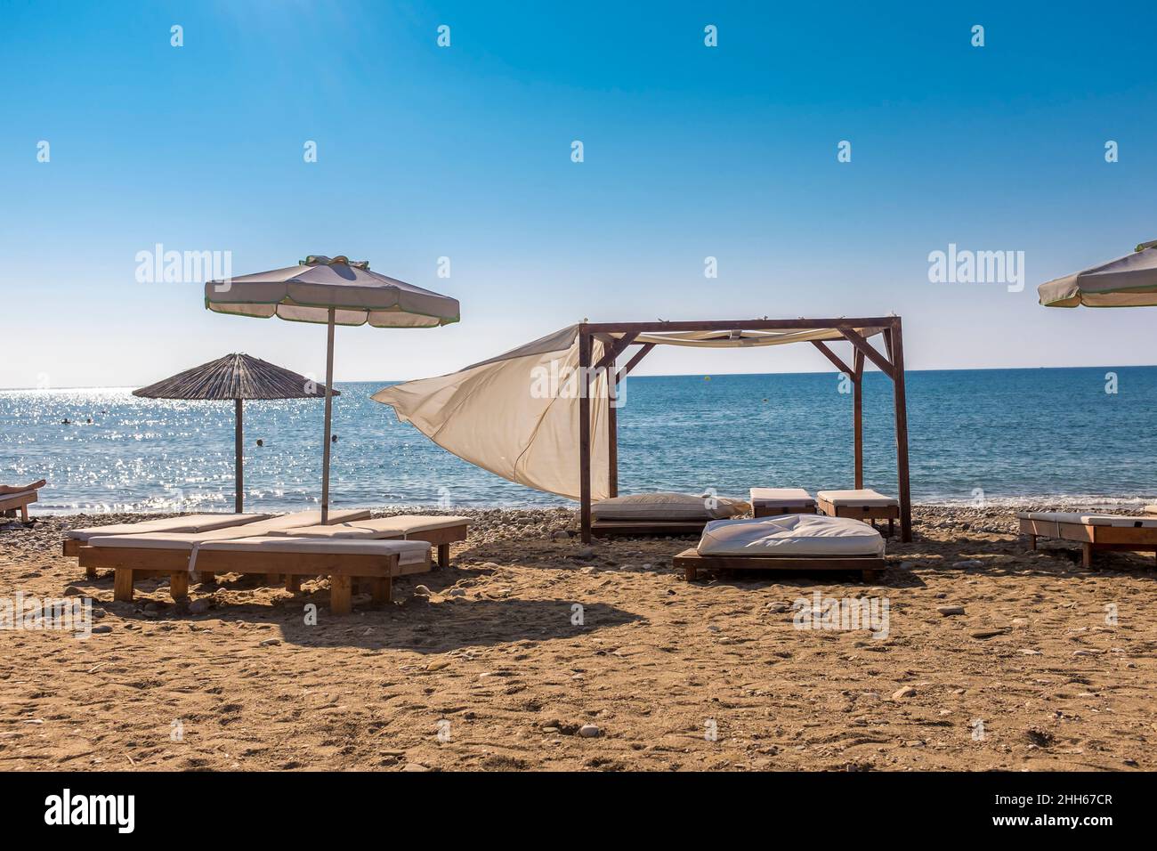 Empty benches and beach umbrellas on sandy coastal beach Stock Photo ...