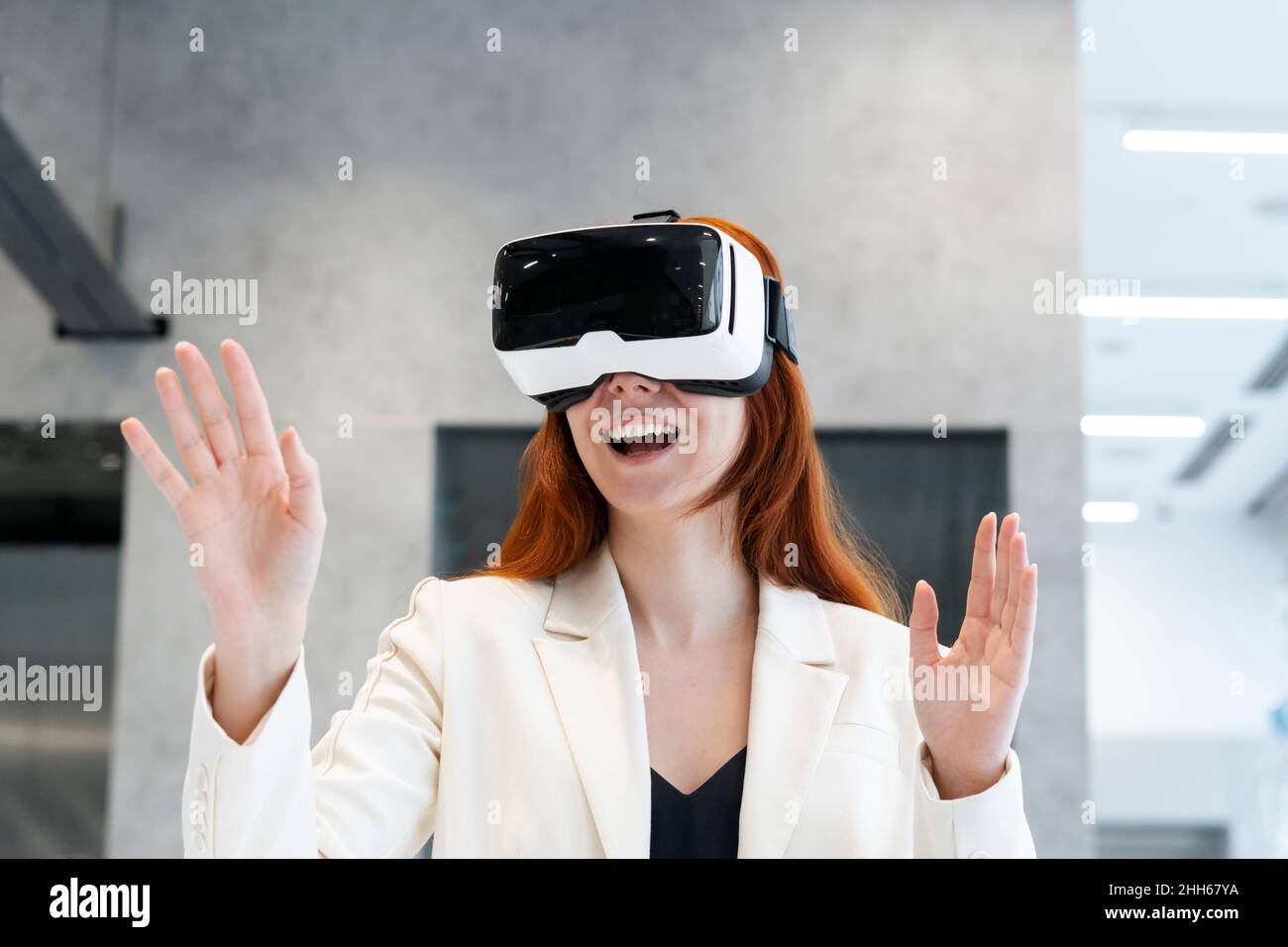 Excited working woman wearing virtual reality simulator gesturing with ...