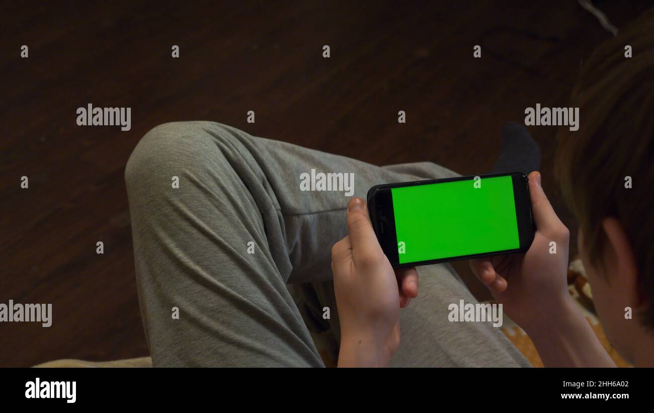 Attractive young man looking his cell phone's blank green screen, while ...