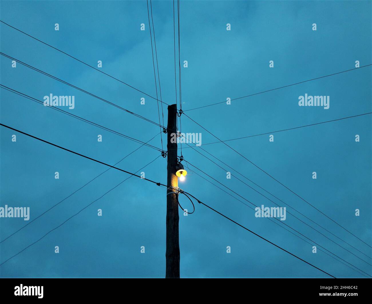 Wire pole and lantern. Light bulb at dusk on a pole. Wallpaper light ...