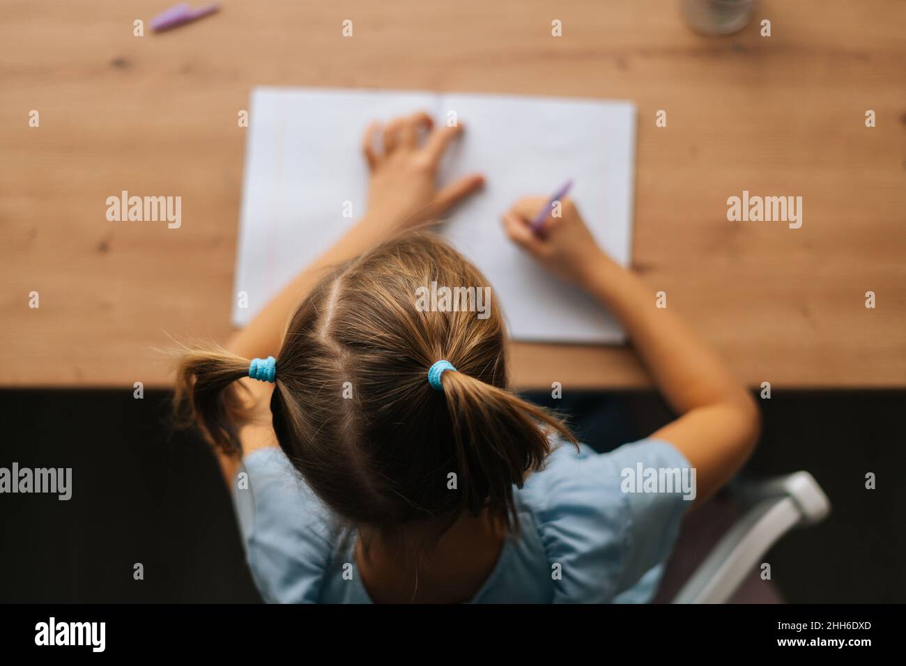 High-angle view of focused primary little child girl doing homework ...