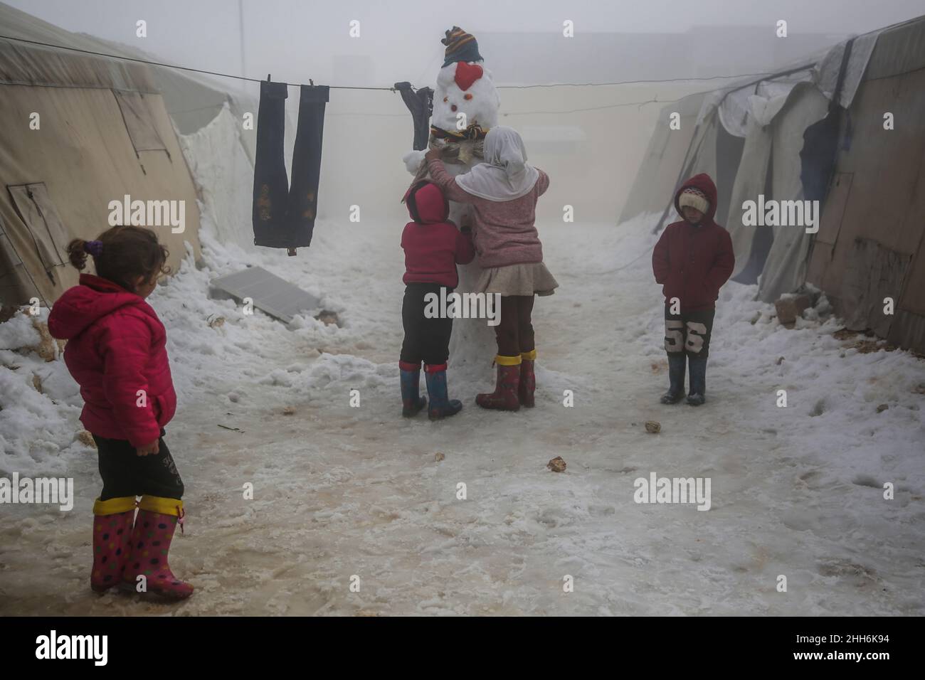 Salqin, Syria. 23rd Jan, 2022. Syrian displaced children make a snowman ...