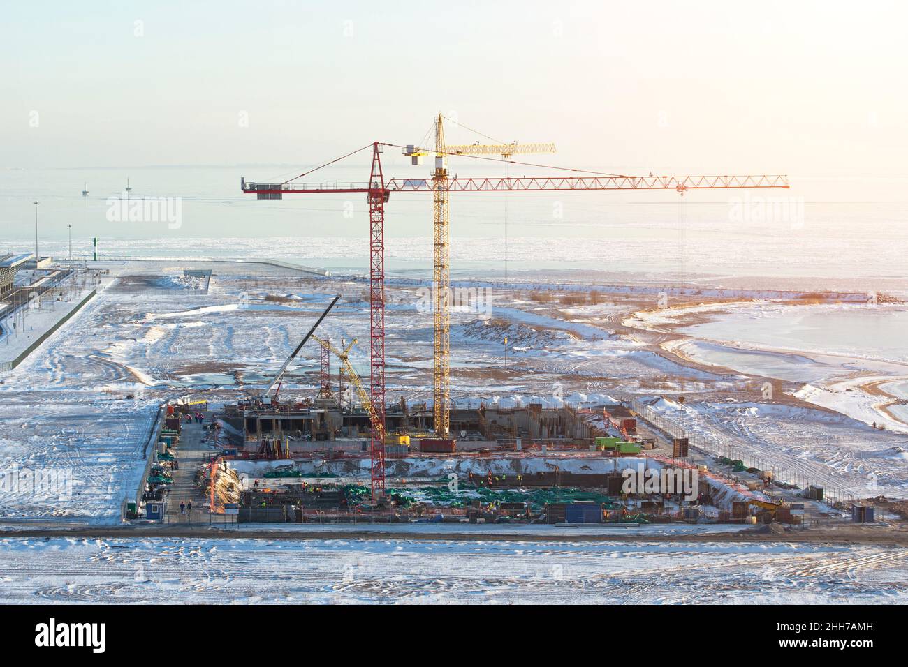 Cranes at the construction site on the shore of the snow of the frozen ...
