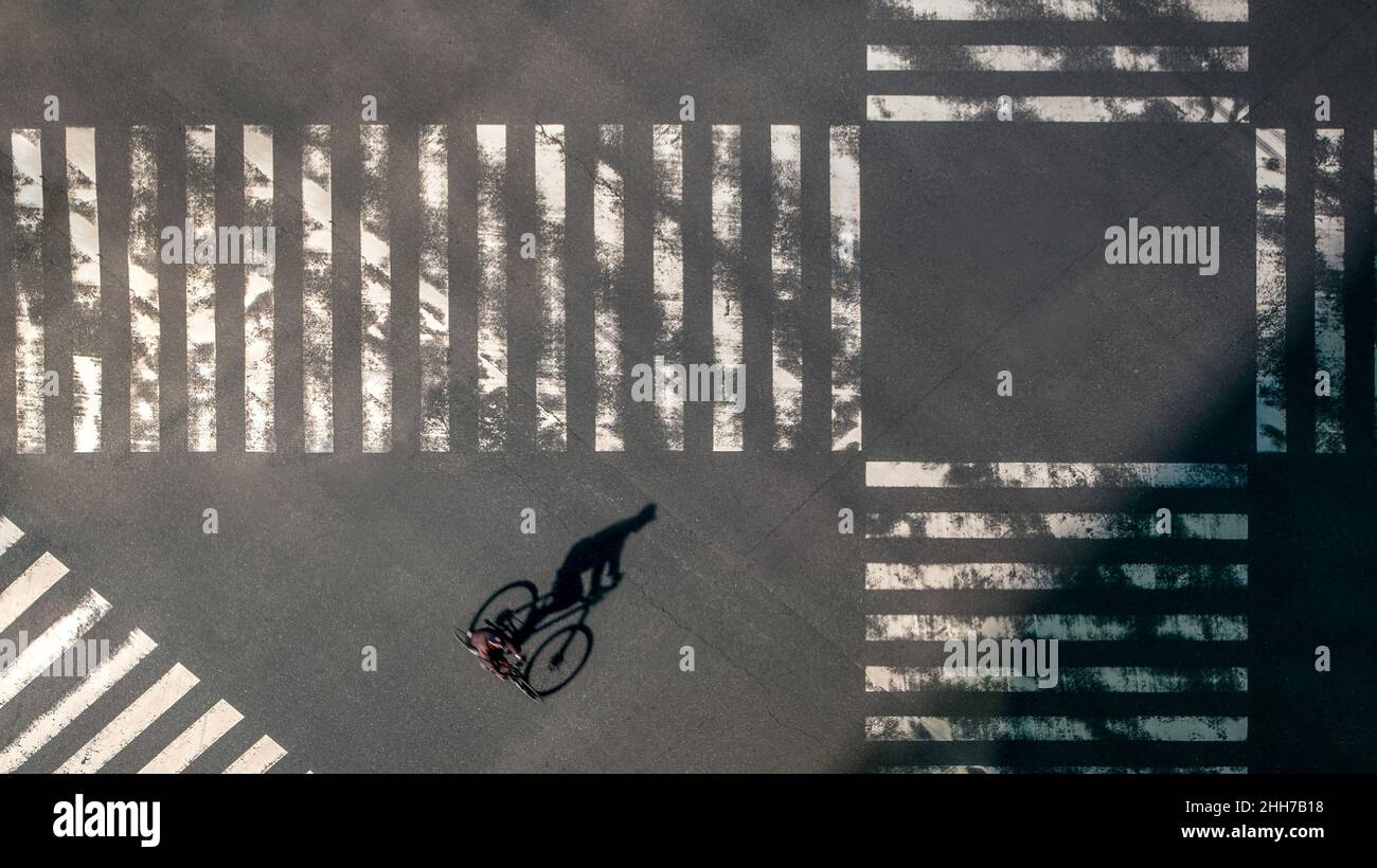 Elevated view over a biker man on pedestrian crossing in road ...