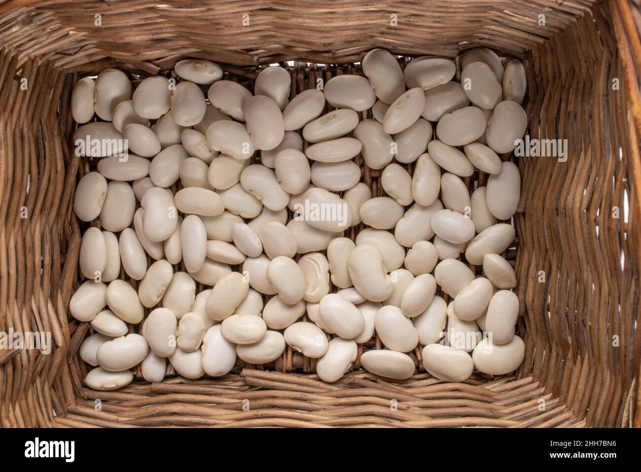 Dried grains of organic white beans in a basket of vines, top view ...