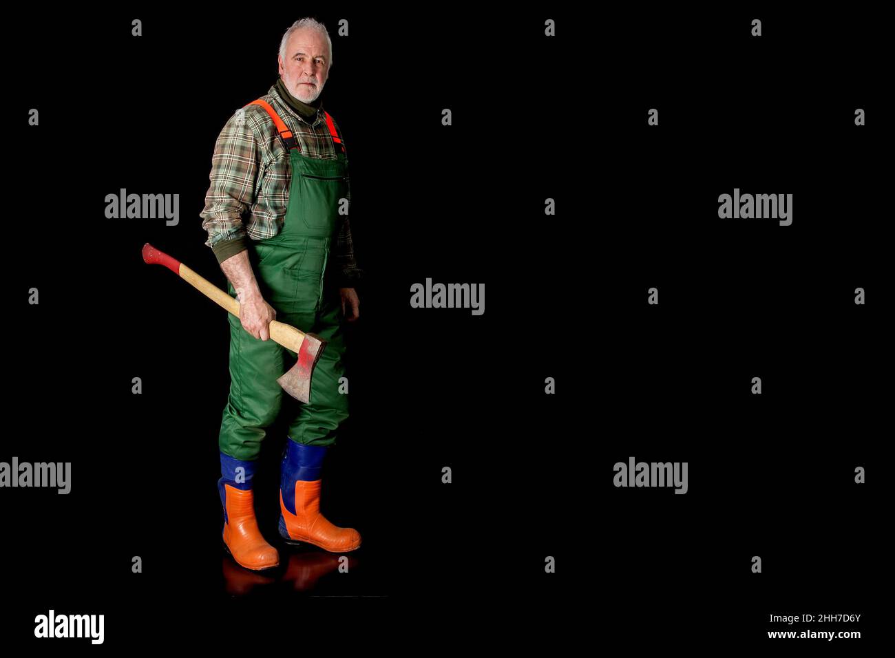A woodcutter stands with his ax and cut-resistant boots in front of a ...