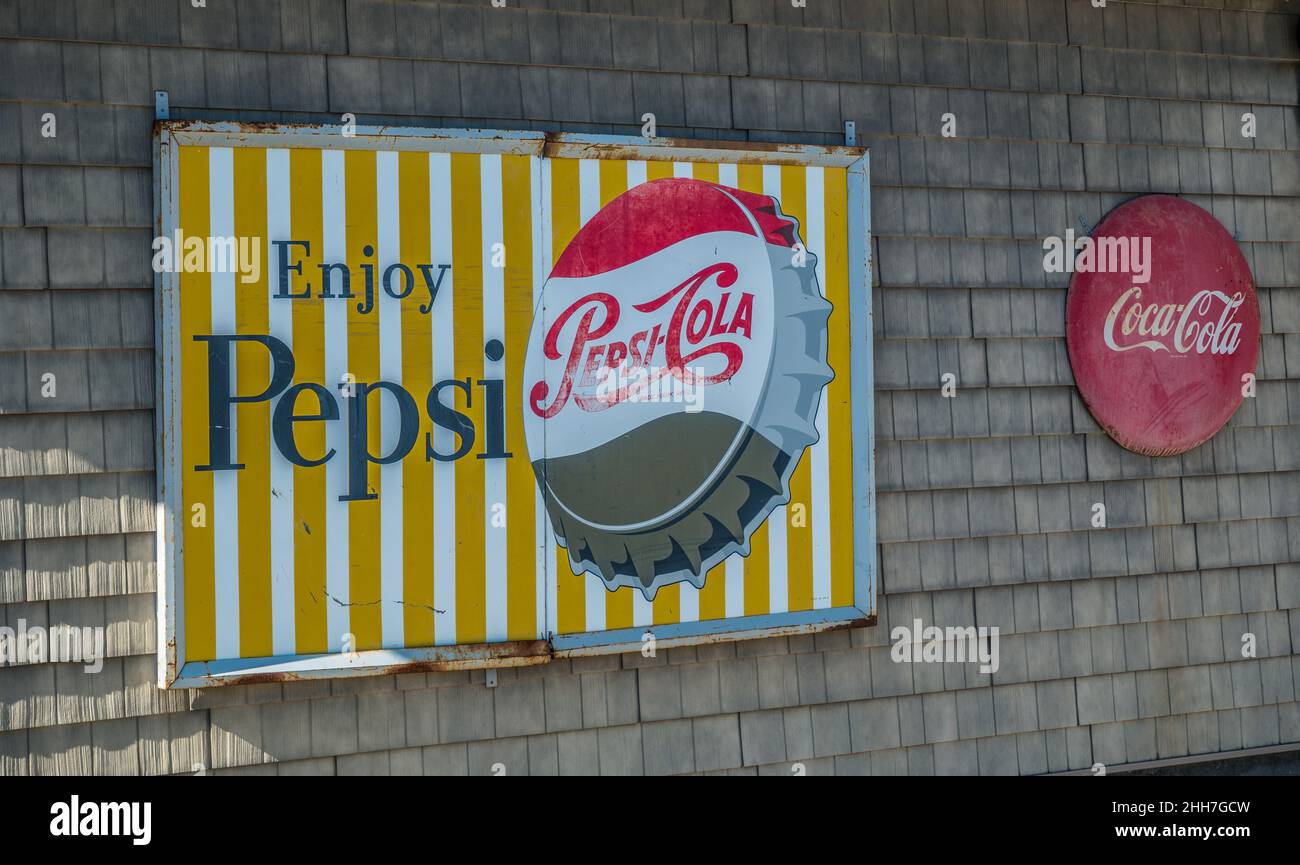 An old large pepsi sign with a soda cap and a round smaller coca-cola ...