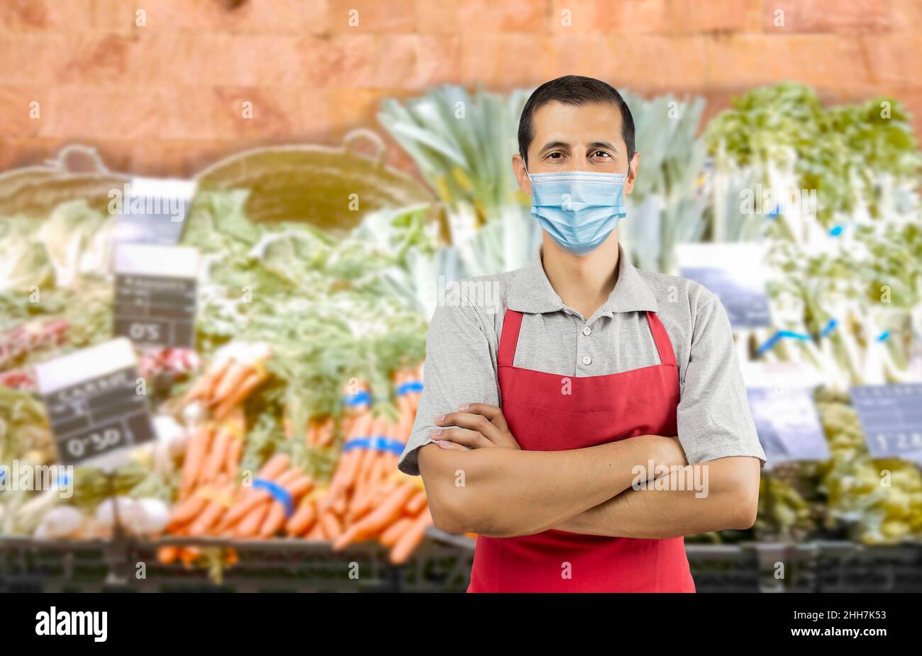 Latin American worker with red apron at a supermarket restocking the ...