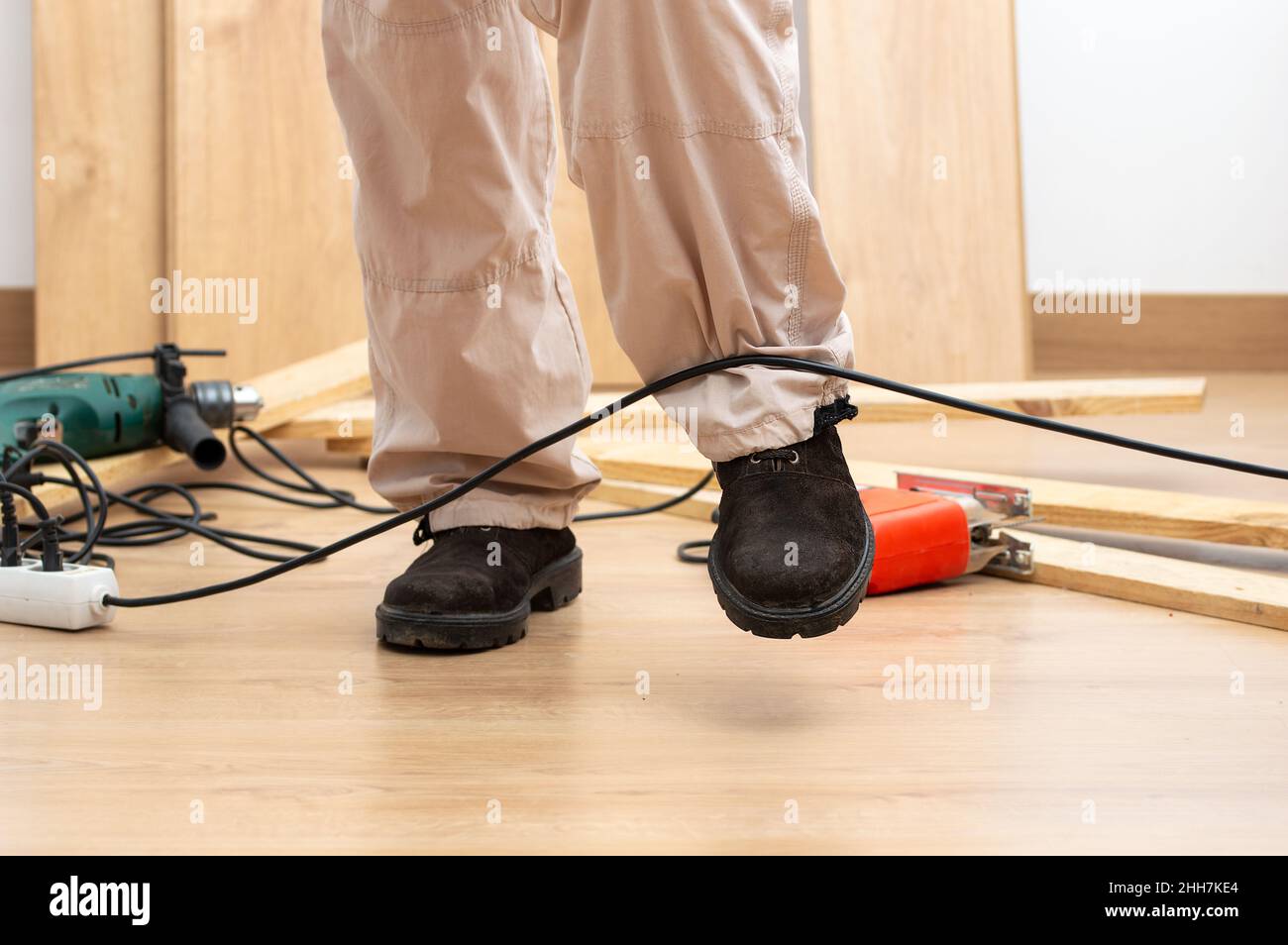 Close up of a carpenter legs stumbling with an electrical cord at house ...
