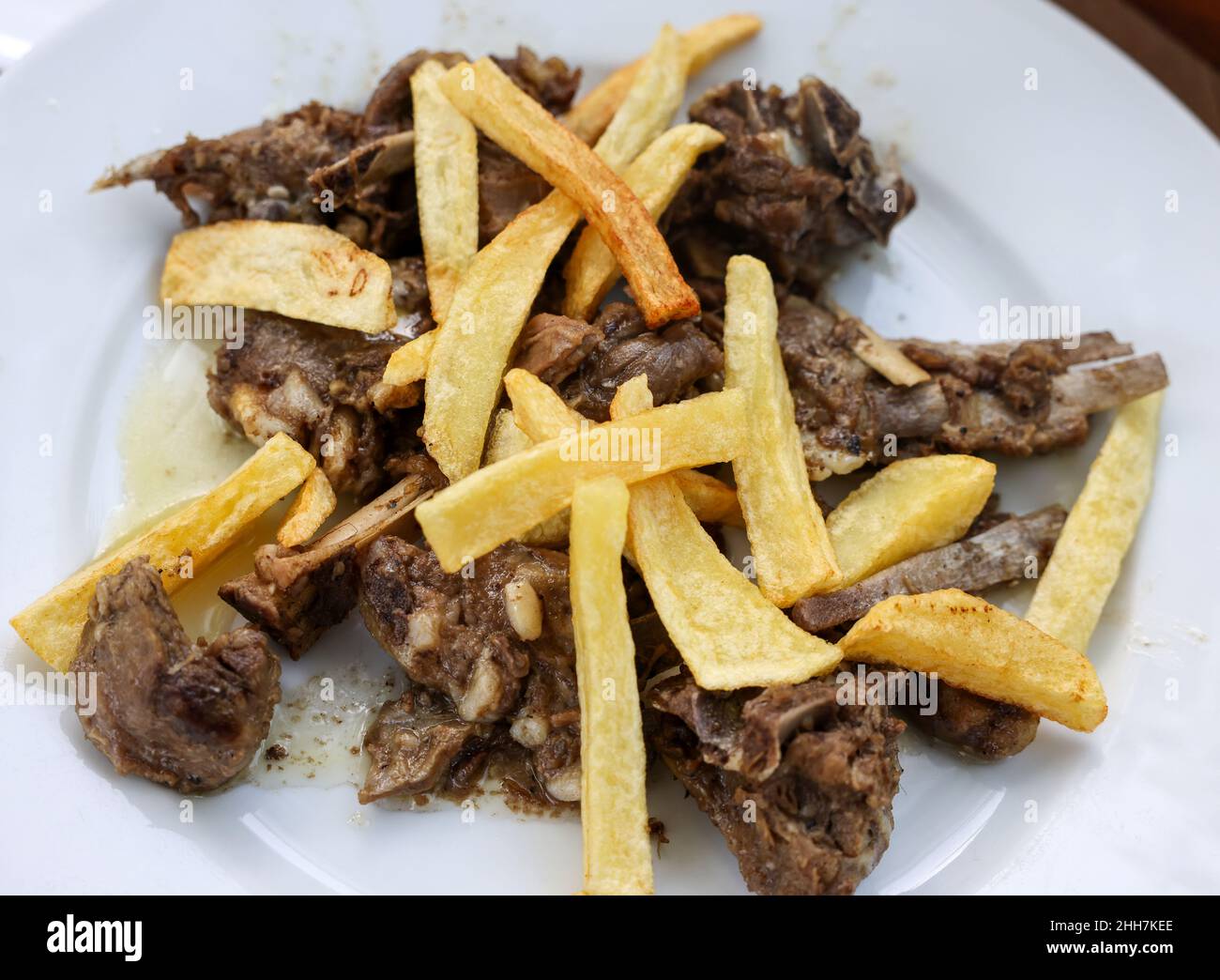 grilled goat with fries on a white plate Stock Photo - Alamy
