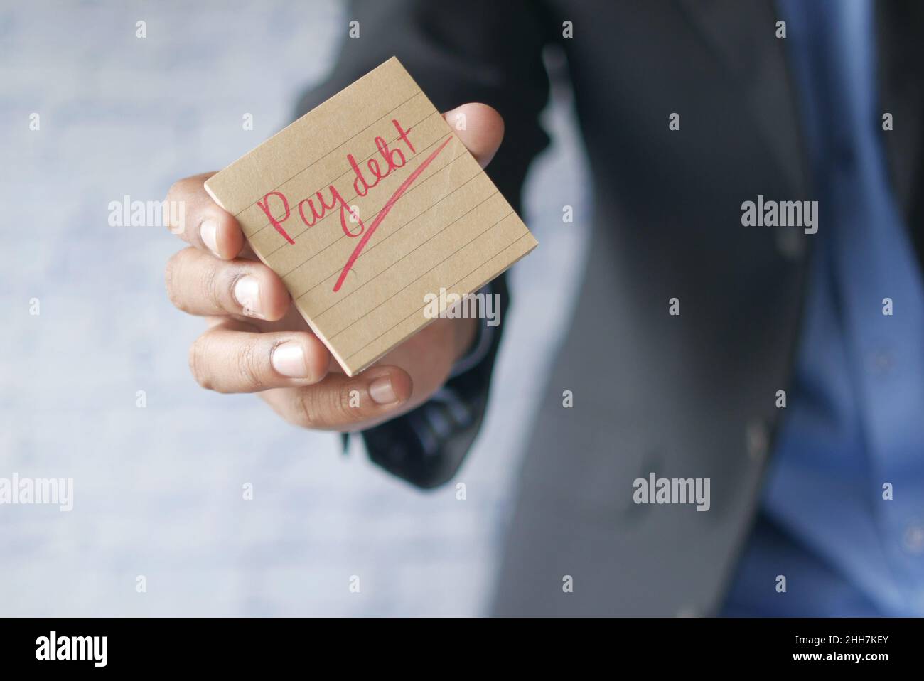 young man hand hold a sticky note with pay debt text Stock Photo - Alamy