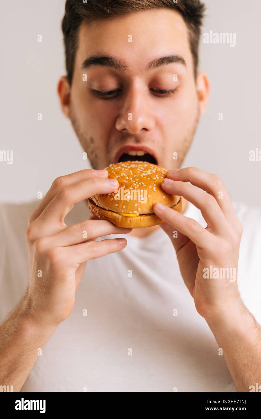Vertical cropped shot of hungry young man with enjoying eating ...