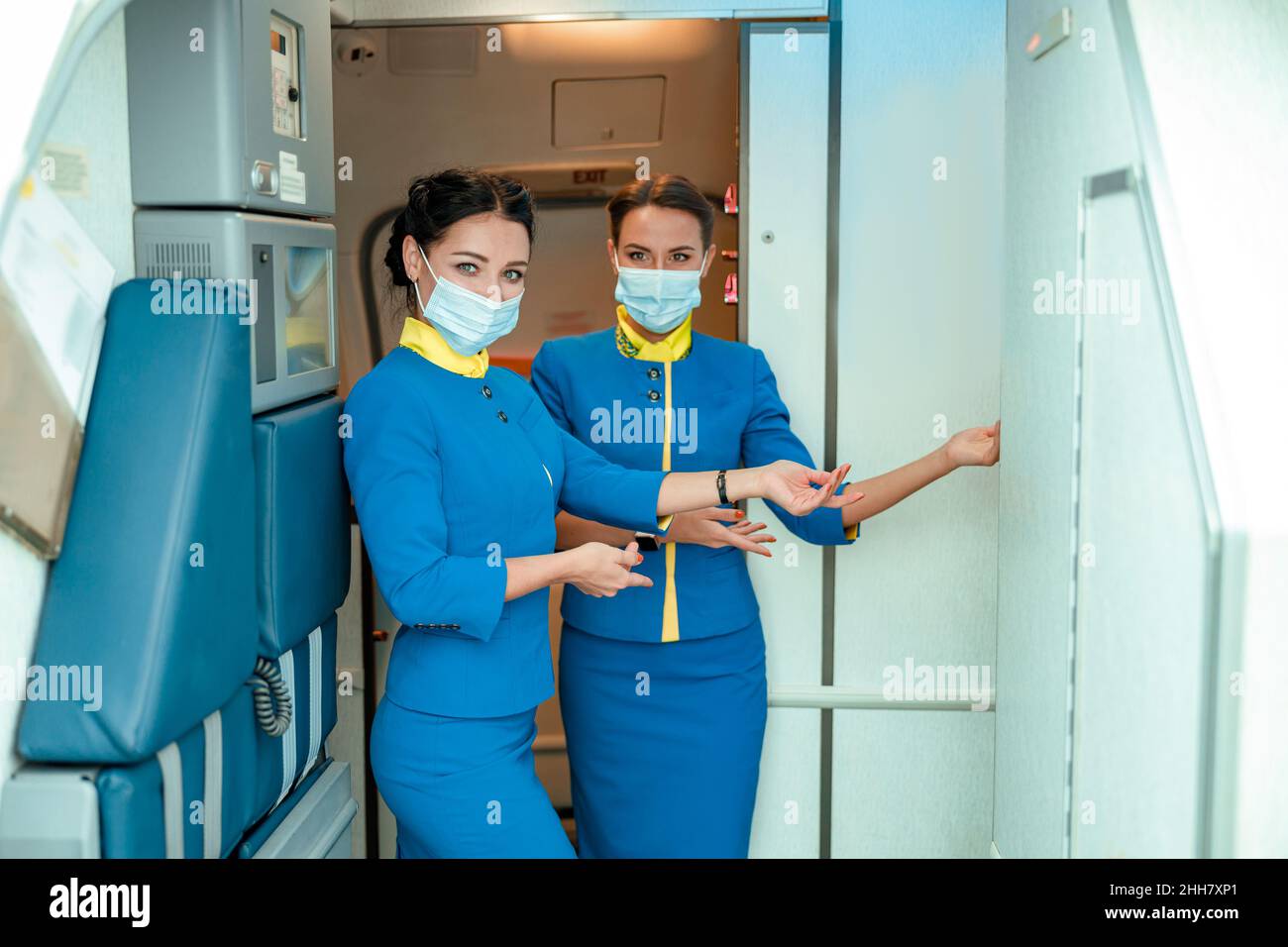 Flight attendants in medical masks inviting on board of airplane Stock ...