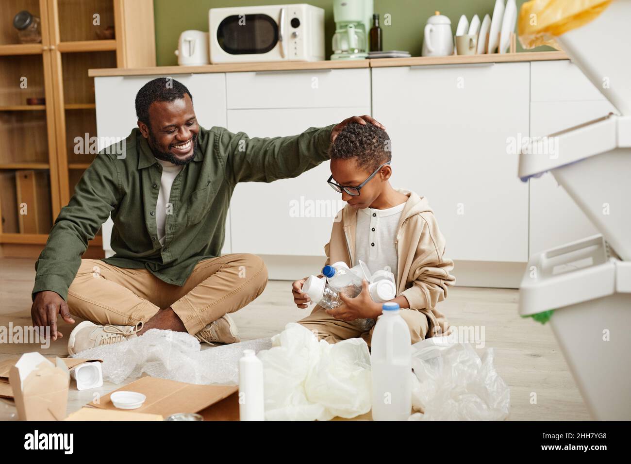 Full length portrait of happy African-American father and son sorting ...