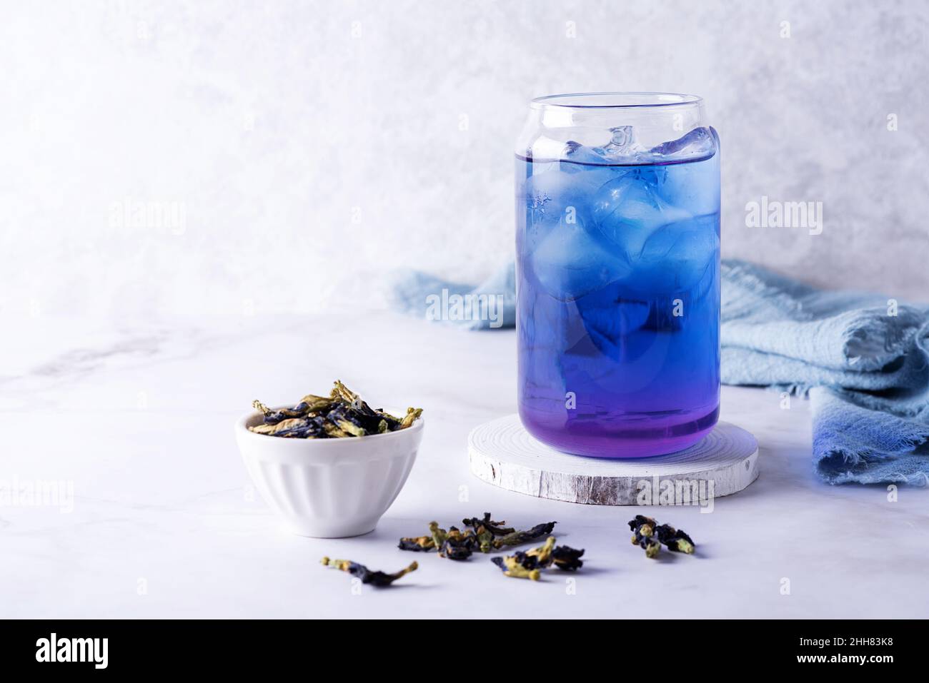 Iced butterfly pea flower tea and dry clitoria ternatea petals on white ...